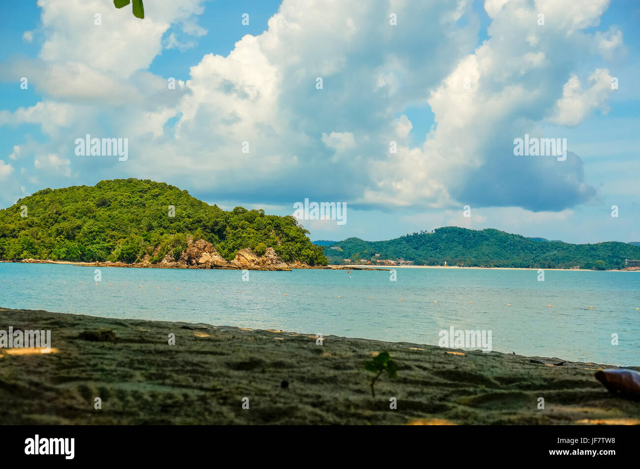 Shaded beach with blue ocean, cloudy sky and an island Stock Photo - Alamy