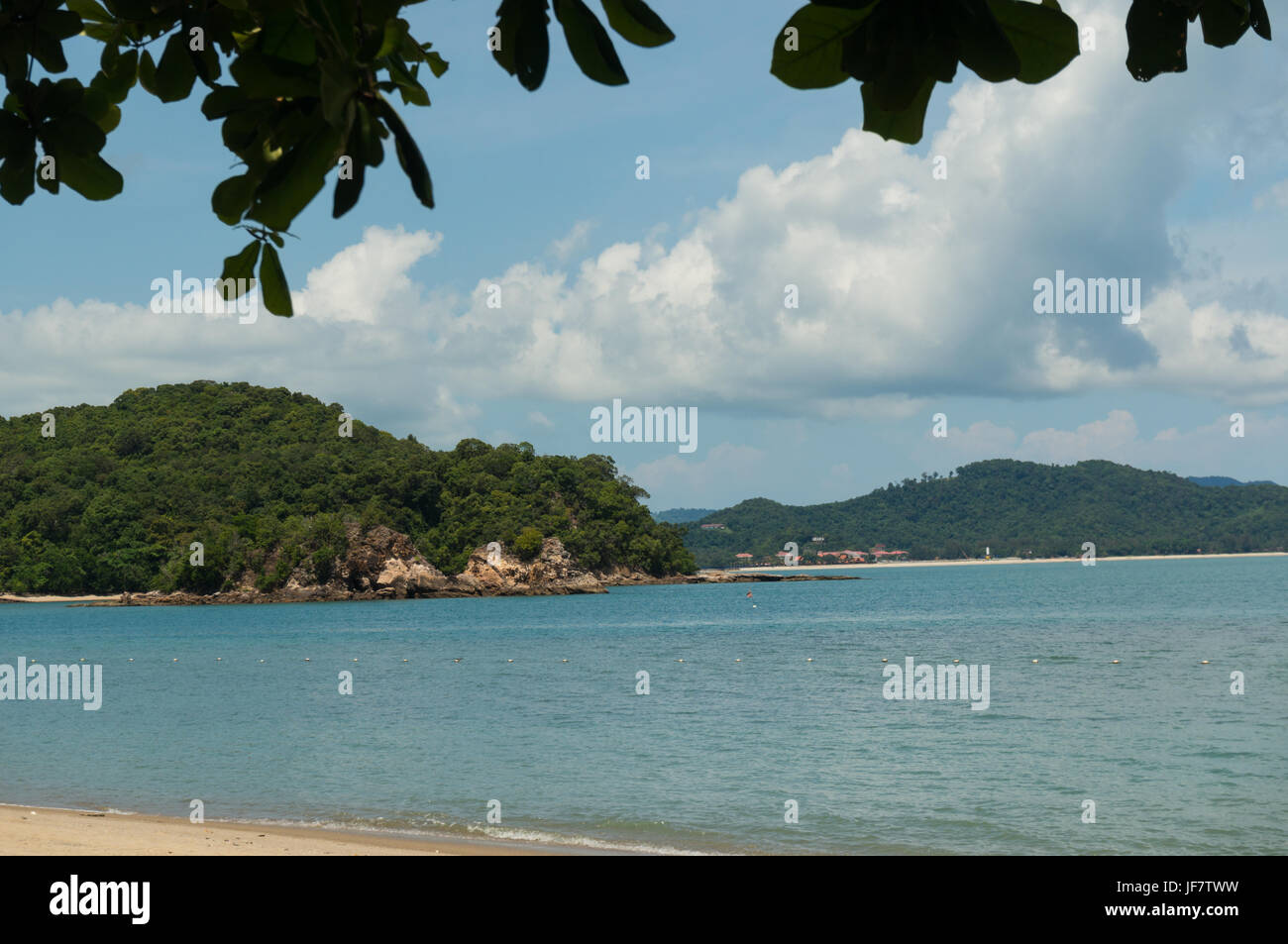 Shaded beach with blue ocean, cloudy sky and an island Stock Photo - Alamy