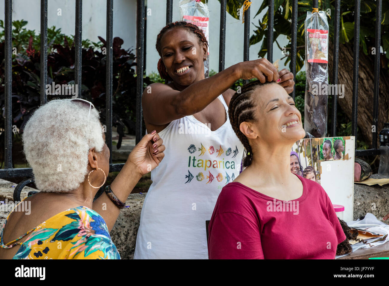 A tourist gets her hair braided in the PLAZA DE ARMAS in HABANA VIEJA ...