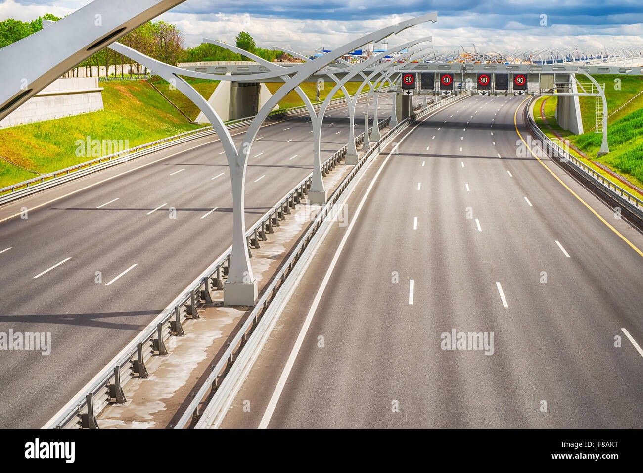 Bright wide high speed highway against distant industrial landscape and ...