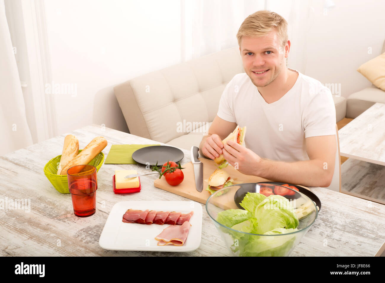 Young man eating a sandwich at home Stock Photo - Alamy