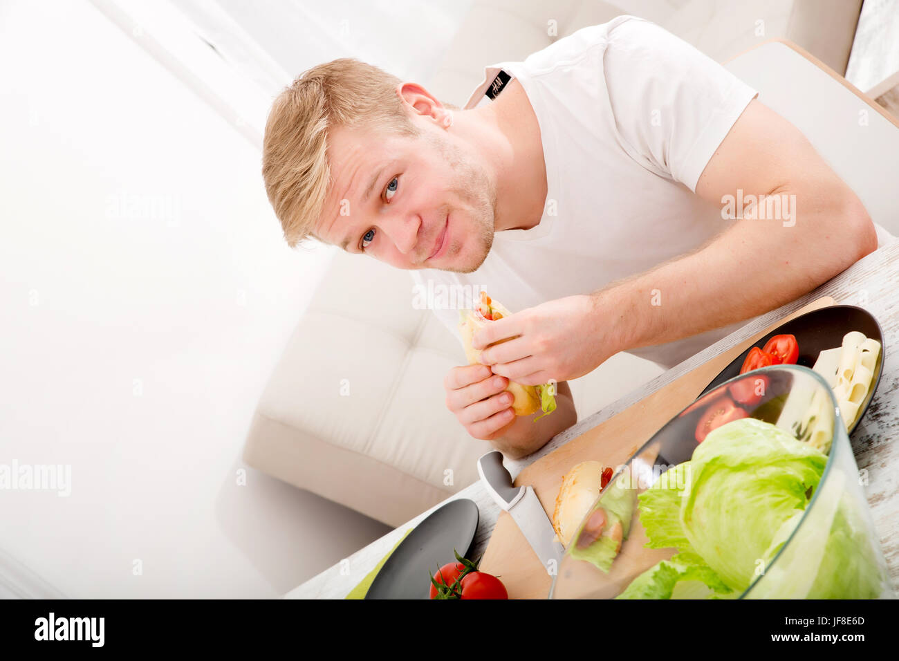 Young man eating a sandwich at home Stock Photo - Alamy