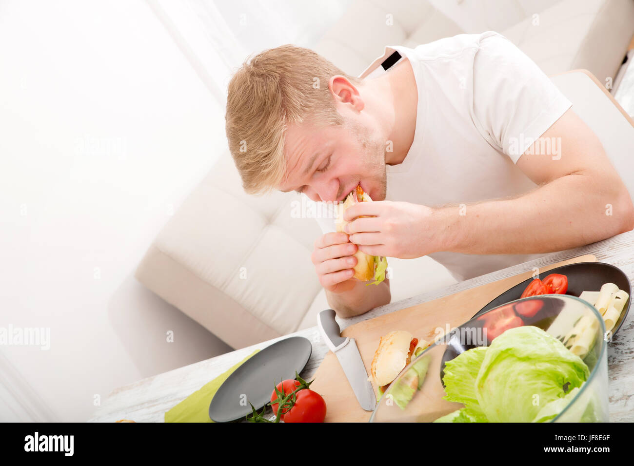 Young man eating a sandwich at home Stock Photo - Alamy