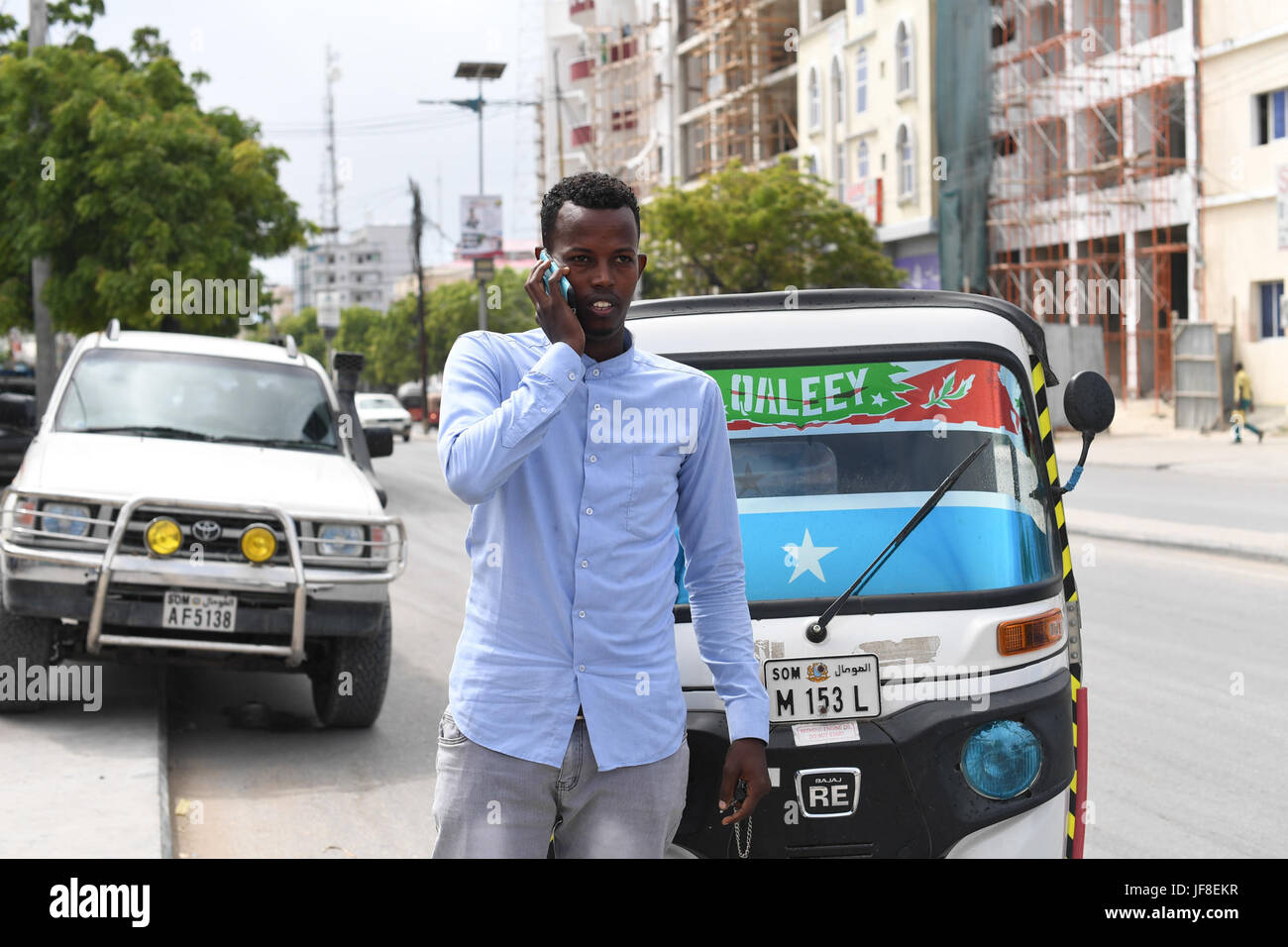 Abdullahi Said Noor, a tuk-tuk driver in Mogadishu, speaks on his phone ...