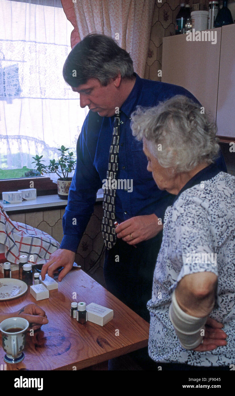 Home visit by GP assisting elderly woman with her medication Stock ...