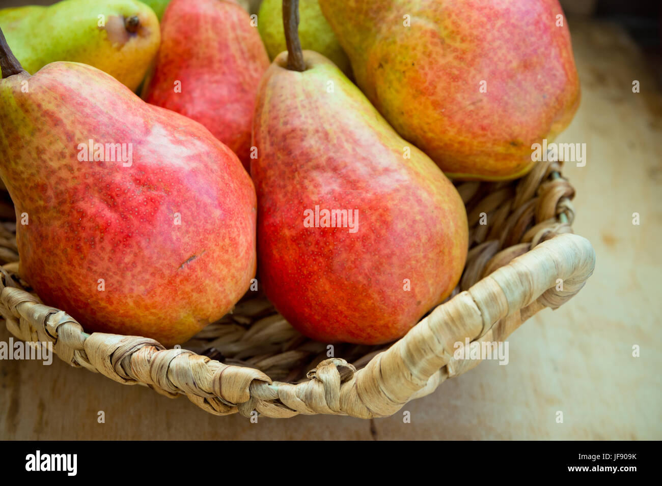 Colorful ripe fresh organic pears in wicker basket on aged wood kitchen ...