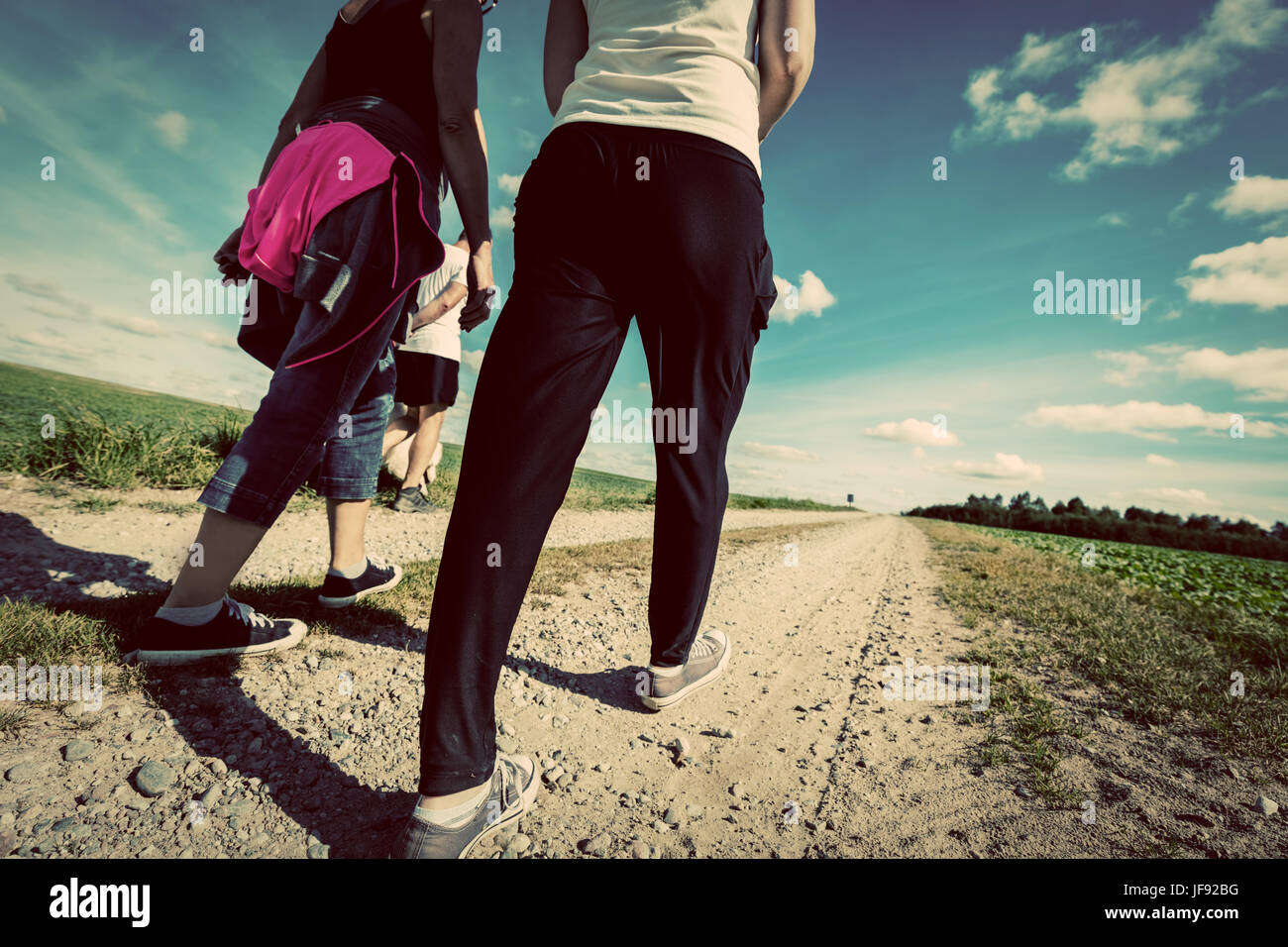 Family walk in countryside on a sunny day. Legs perspective, wide angle ...