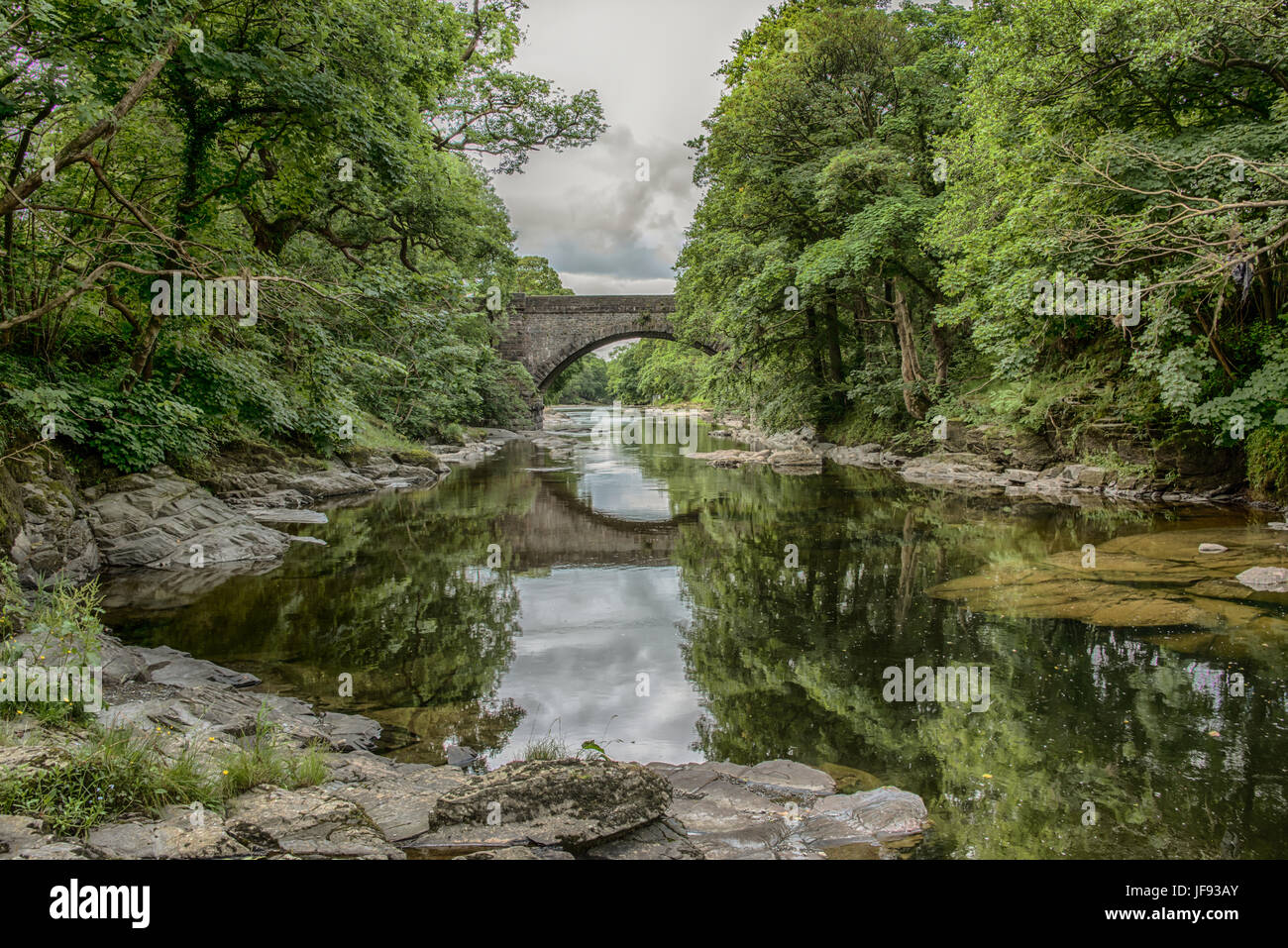 A view down a river with a bridge spanning it and with reflections in ...