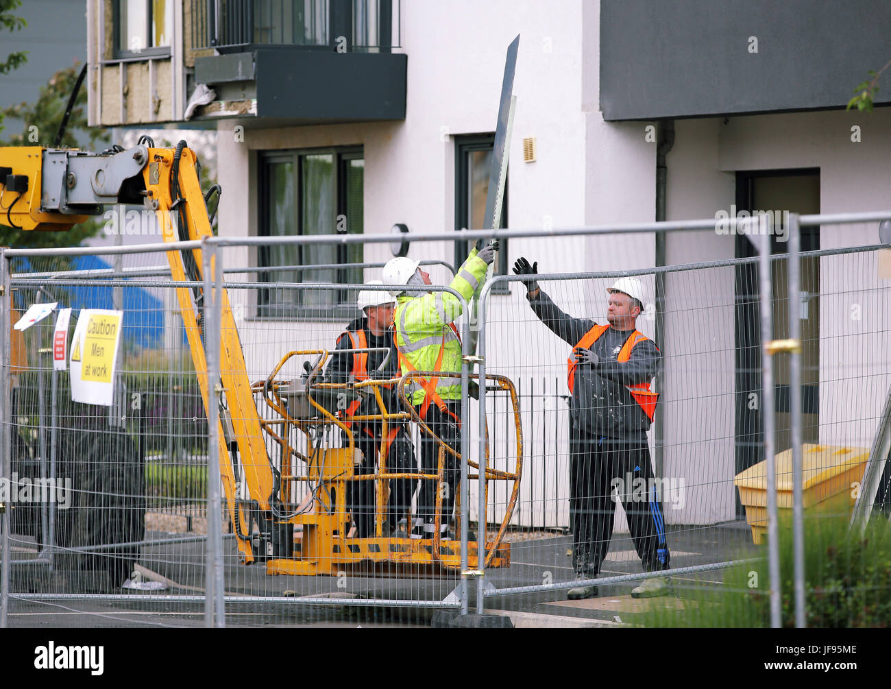 Workers on a cherry picker remove cladding panels from Kennedy Gardens ...