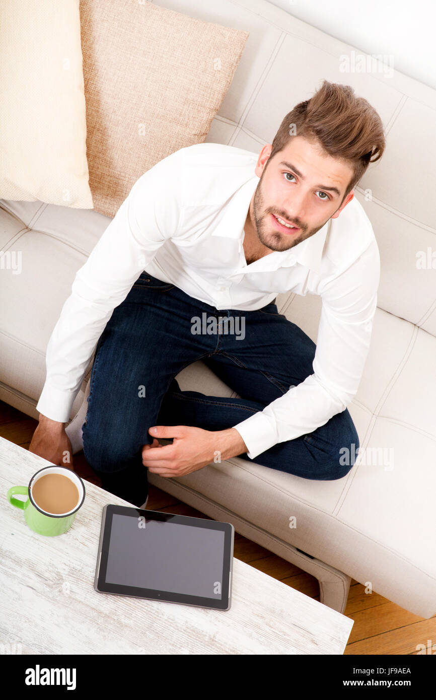 Young man with tablet on couch Stock Photo - Alamy