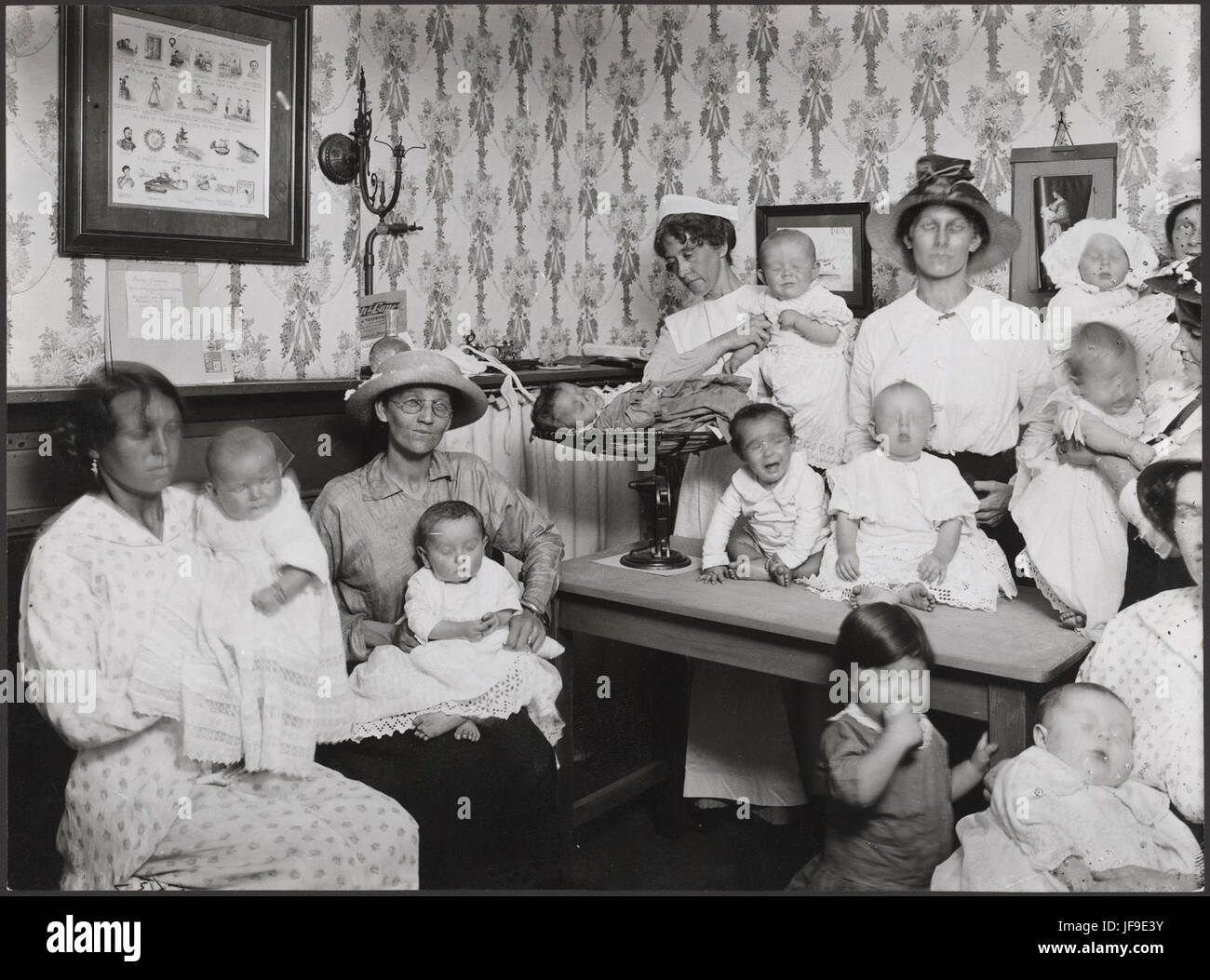 A historical black-and-white photograph of a nurse weighing a baby at ...