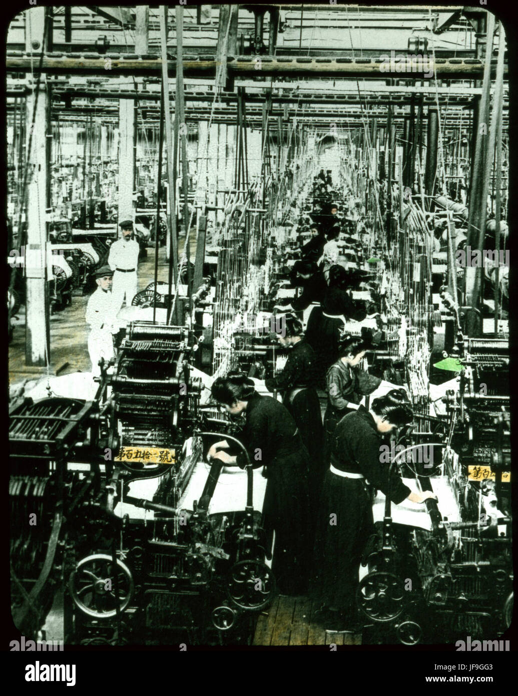 A historical photograph showing workers operating a machine-weaving ...