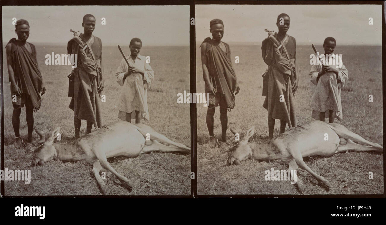 Three young men stand over an antelope carcass, likely from a hunting ...