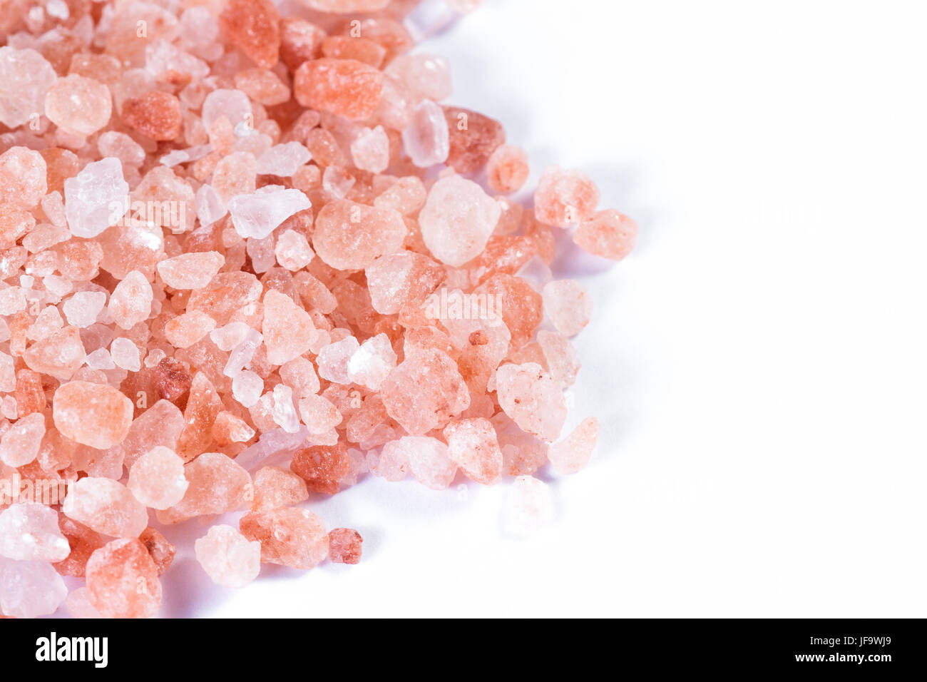 Himalayan pink salt crystals piled and isolated on a white background ...