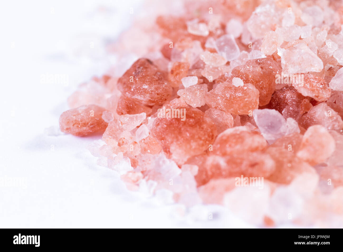 Himalayan pink salt crystals piled and isolated on a white background ...