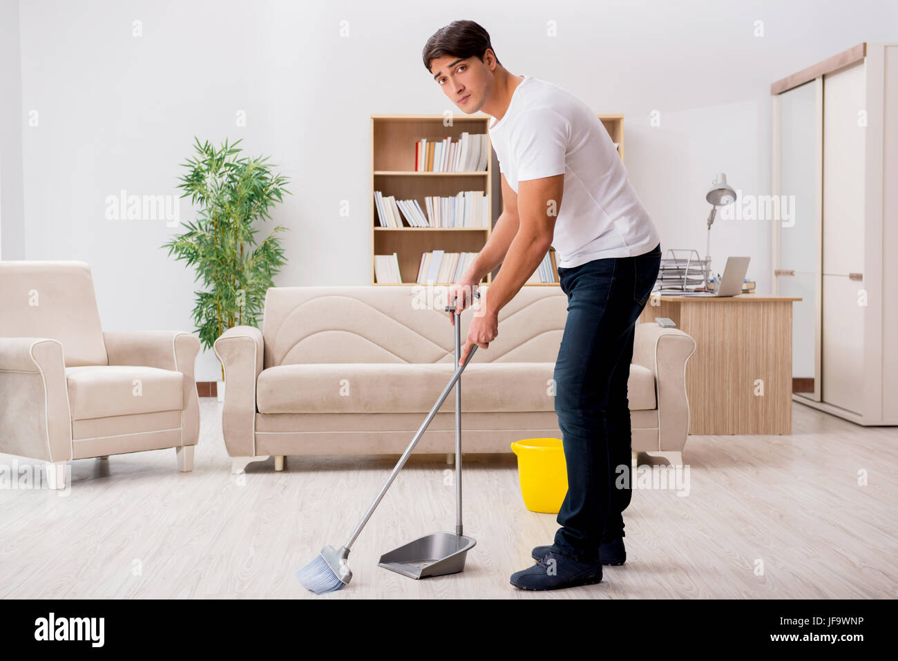 Man cleaning home with broom Stock Photo - Alamy