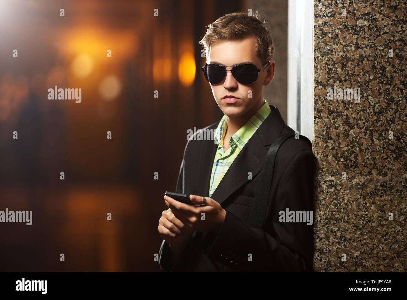 Young man with a mobile phone standing at the wall Stock Photo - Alamy