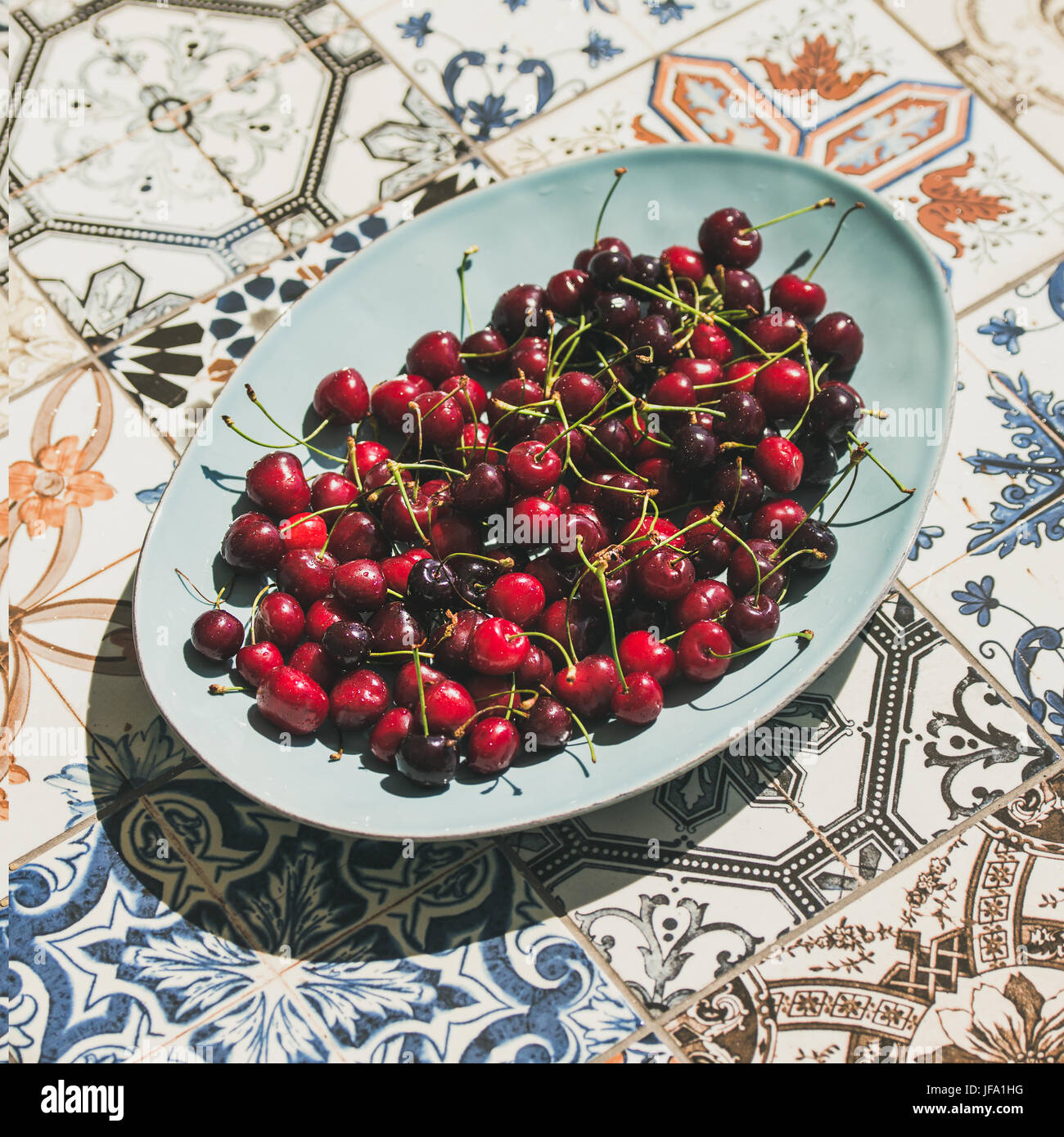 Fresh sweet cherries in plate over oriental ceramic tiles background ...