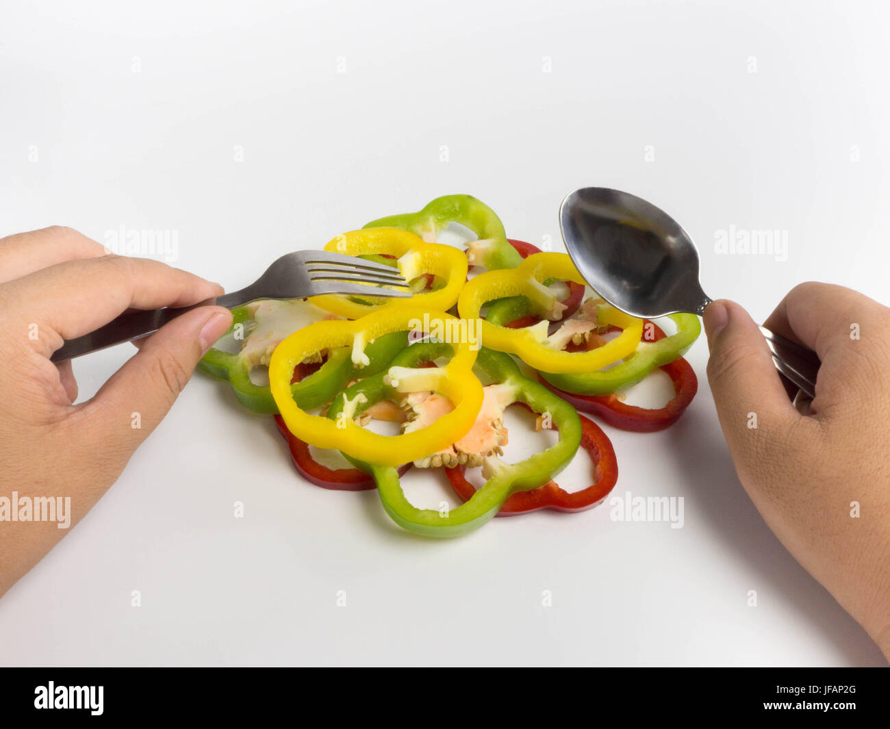 Sliced colored bell peppers with spoon and fork in hands Stock Photo ...