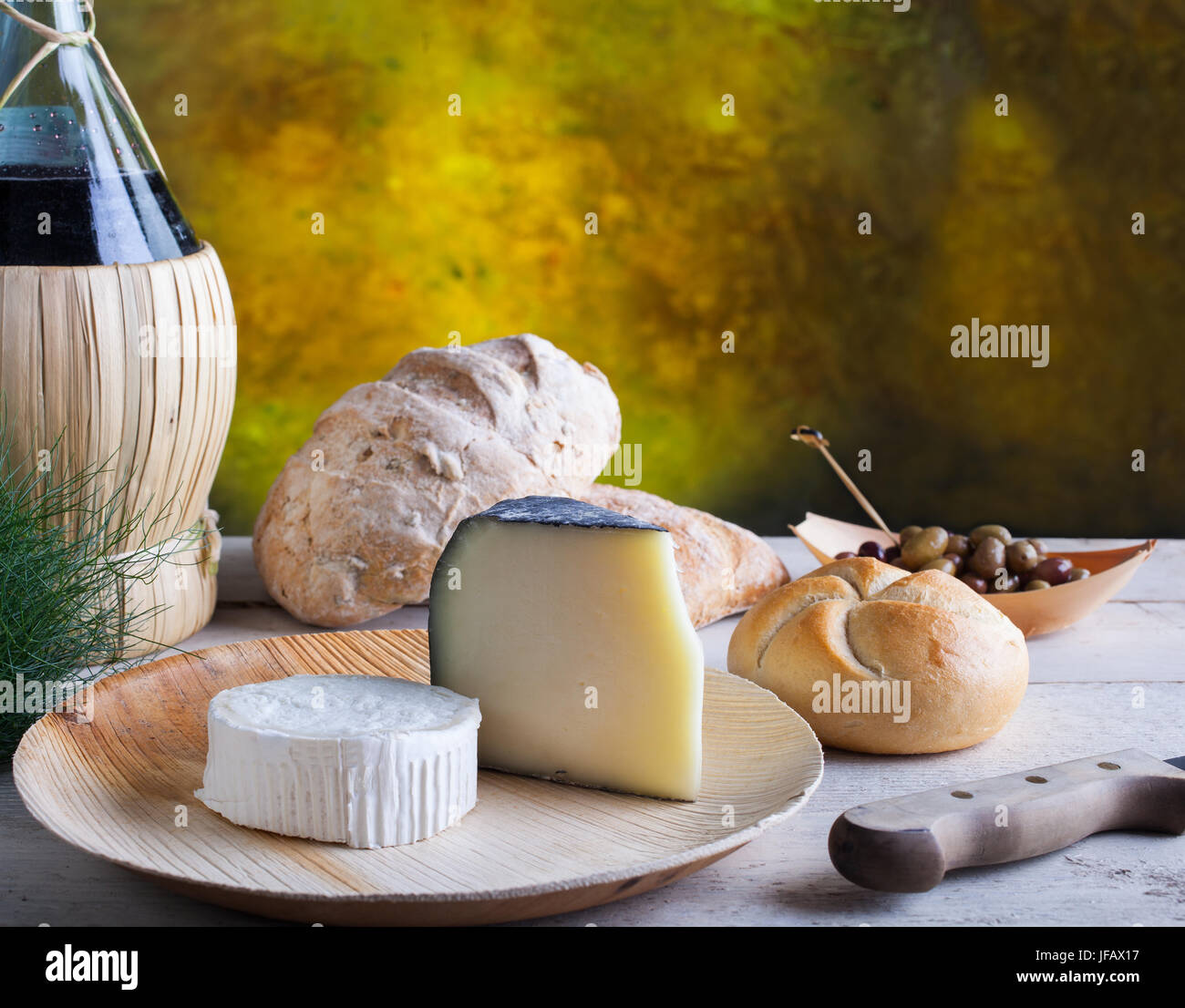 Italian slow food on the white table. Olives, cheese, bread and red ...