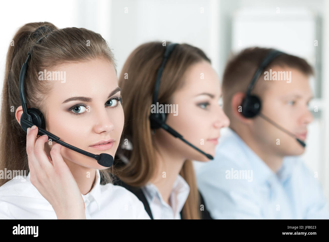 Portrait of call center worker accompanied by her team. Smiling ...