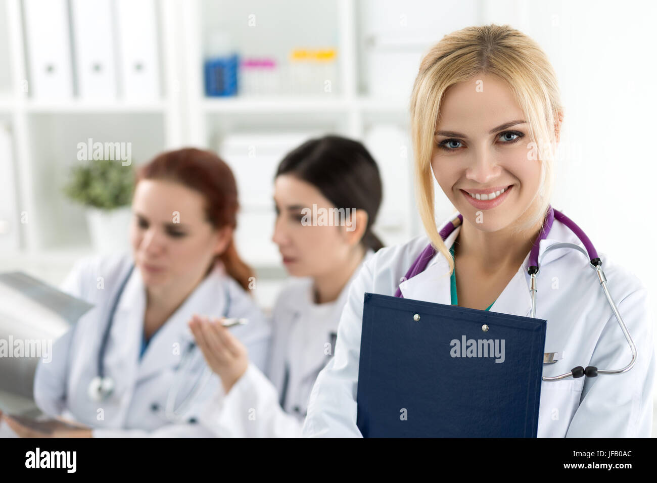 Portrait of smiling female medicine doctor holding blue document folder ...