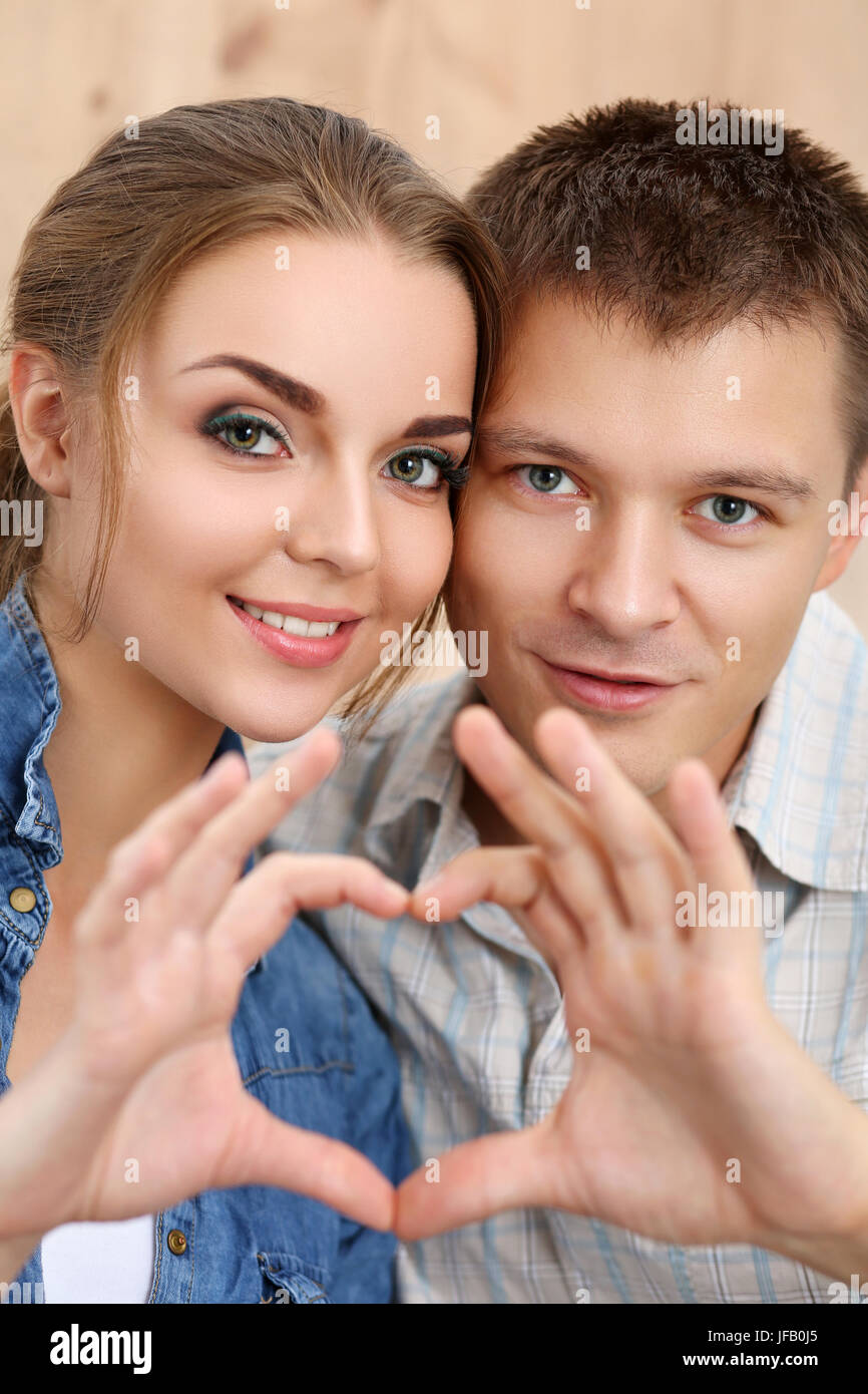 Portrait of smiling beautiful girl and her boyfriend making shape of ...