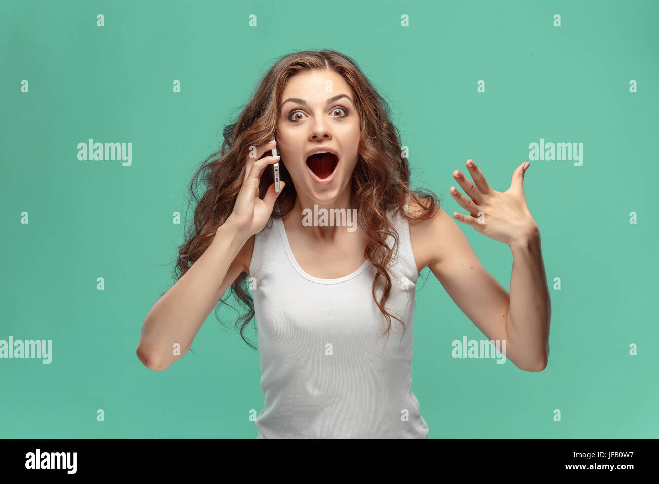 Shocked woman looking at mobile phone on green background Stock Photo ...