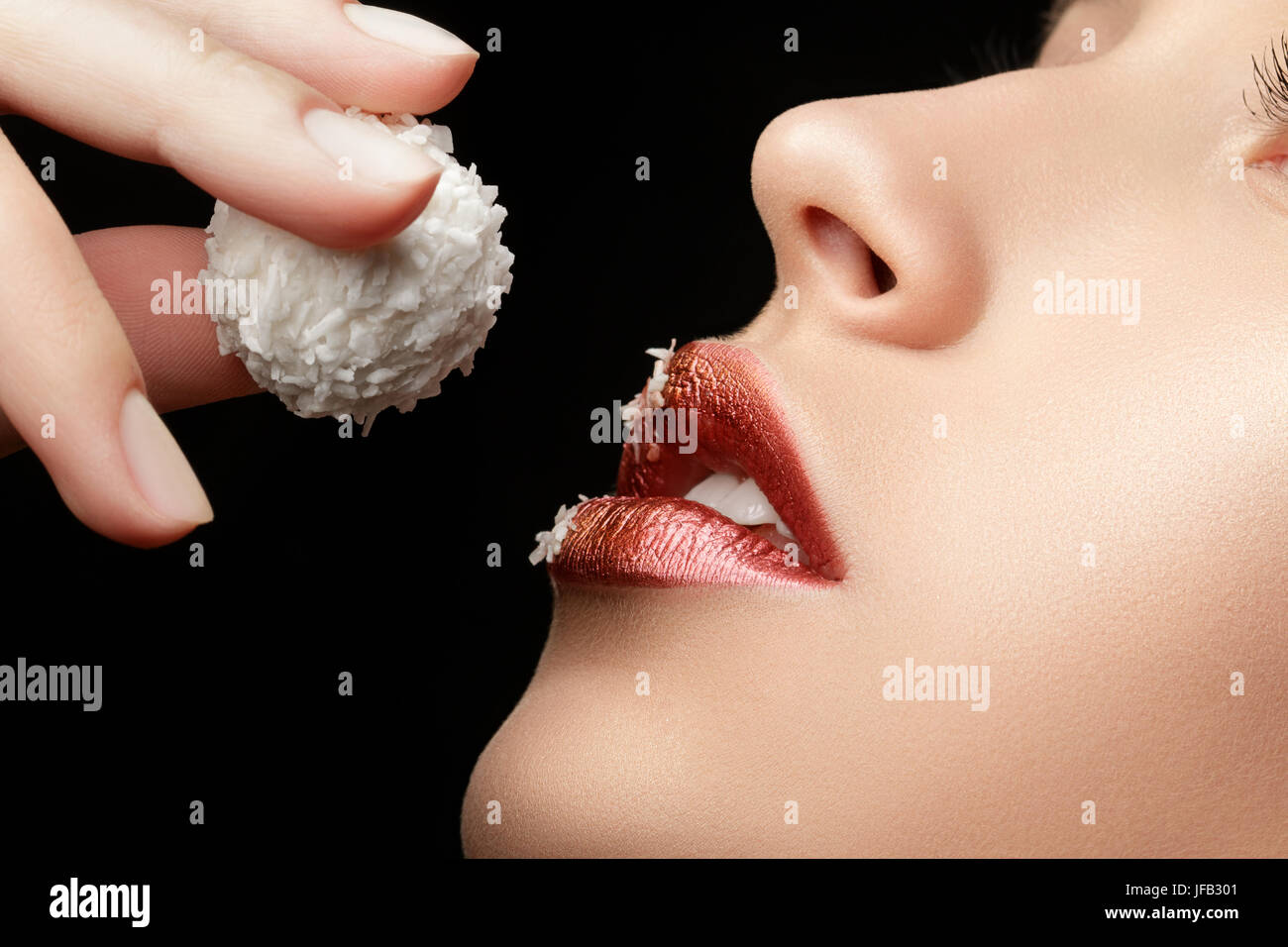 Close up view of female lips eating coconut candy. Natural desserts ...