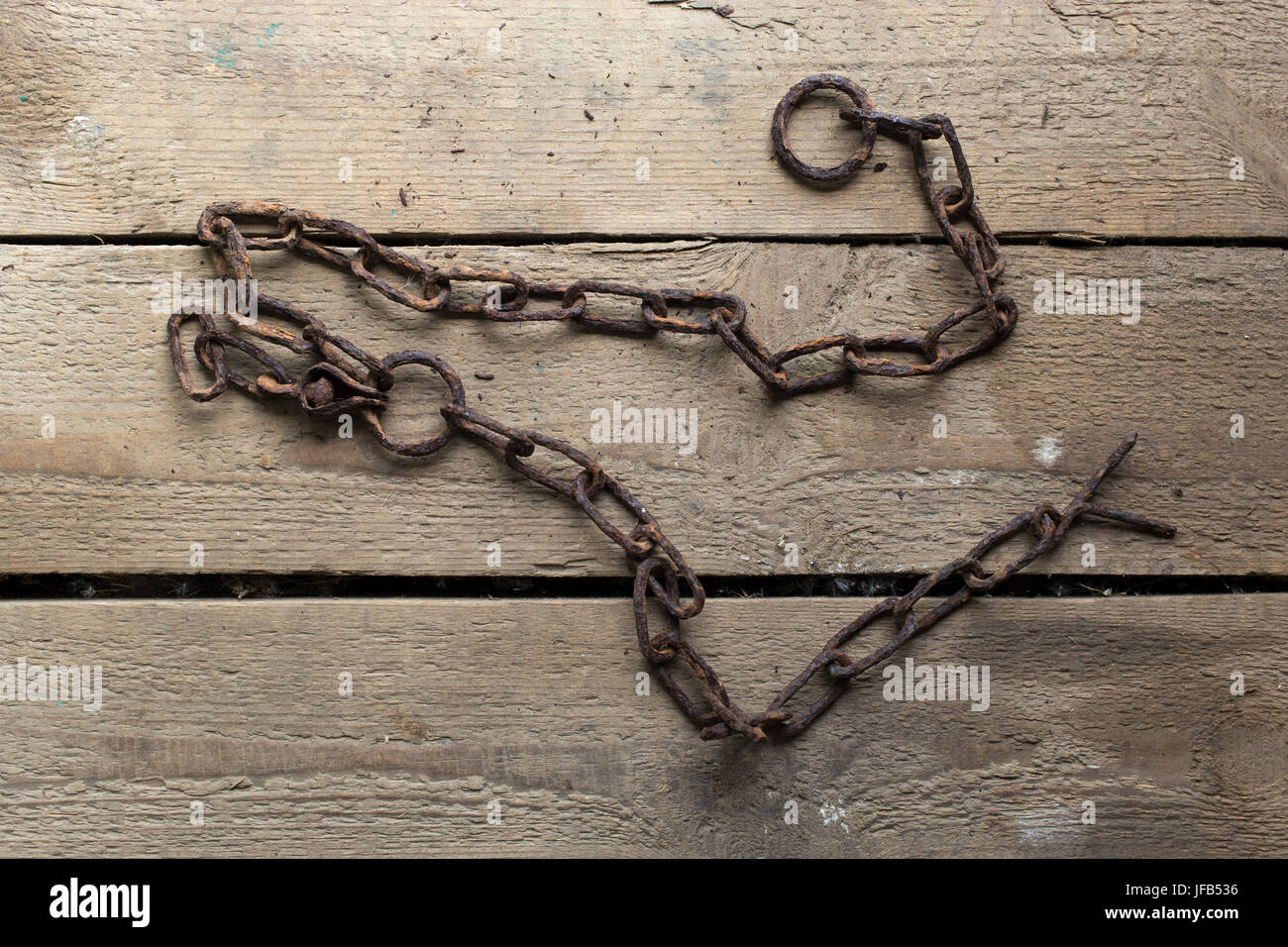 Rusty old metal chain on a wooden background. Rusty links of the chain ...