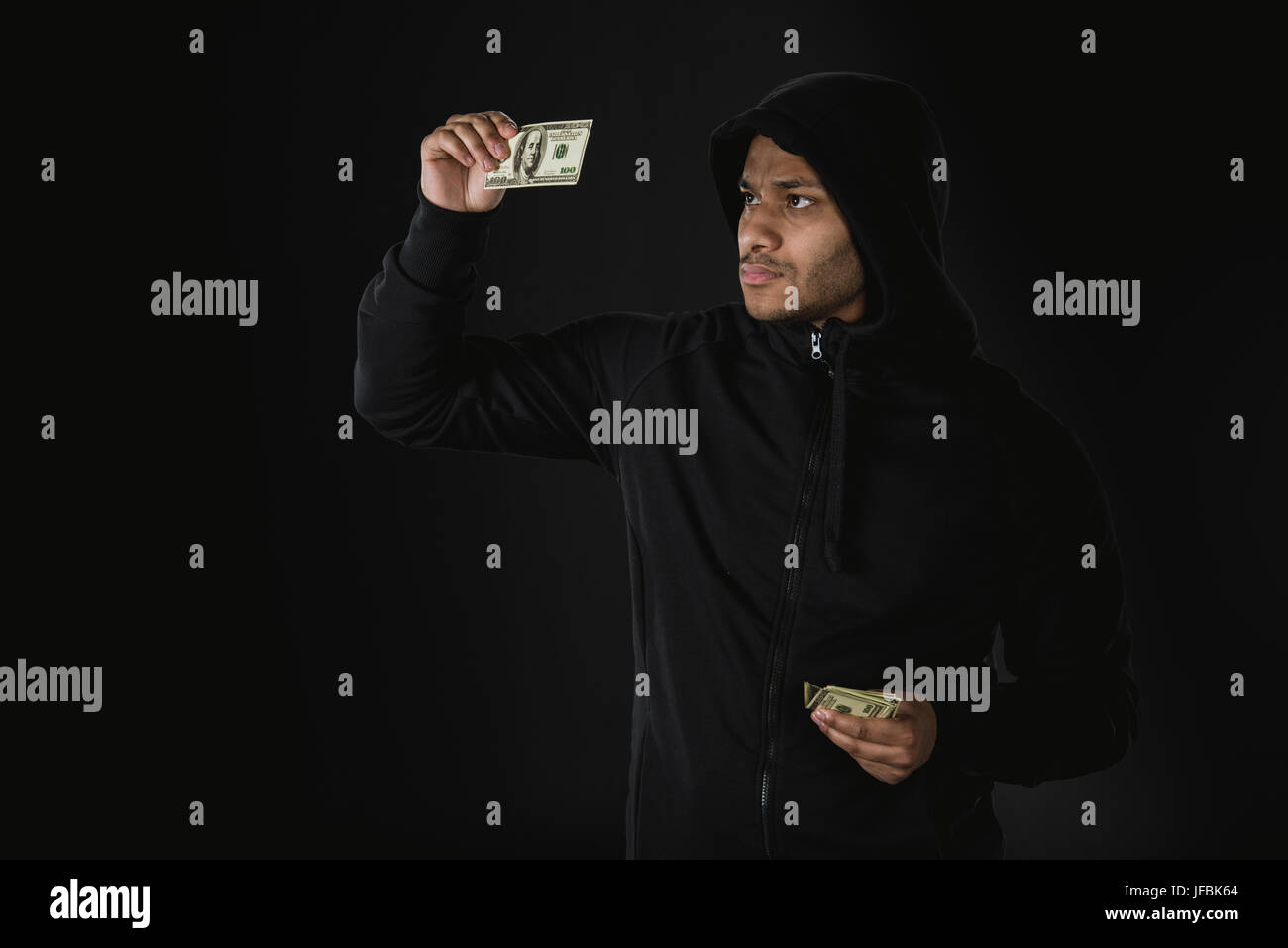 young african american robber in zoodie holding money isolated on black ...