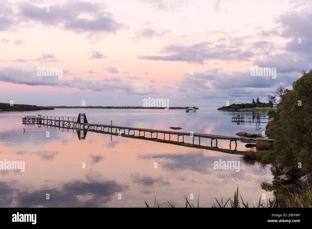 Sunset over a private jetty into the shallow waters of Hardy Inlet ...