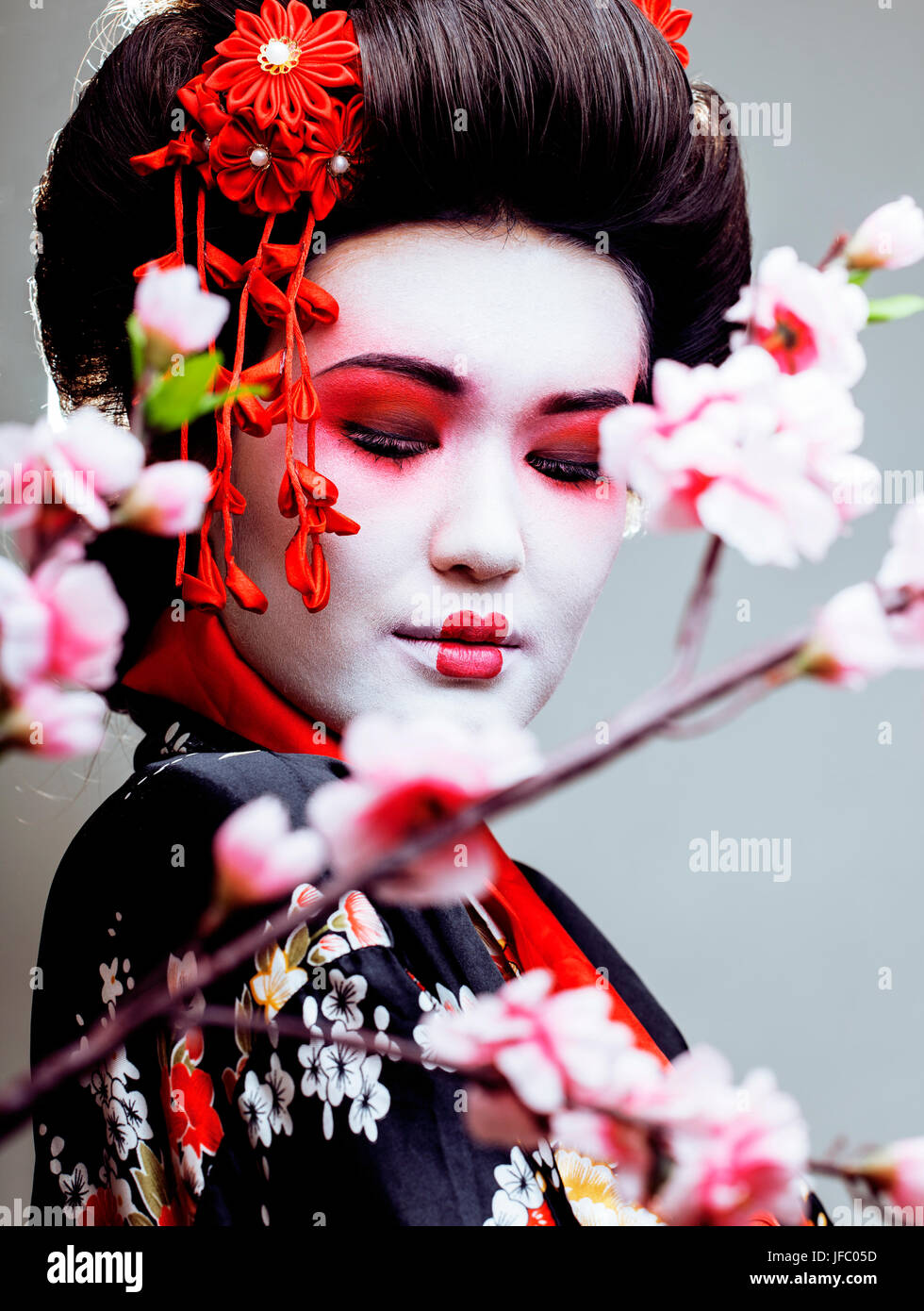 young pretty geisha in kimono with sakura and red decoration design on ...