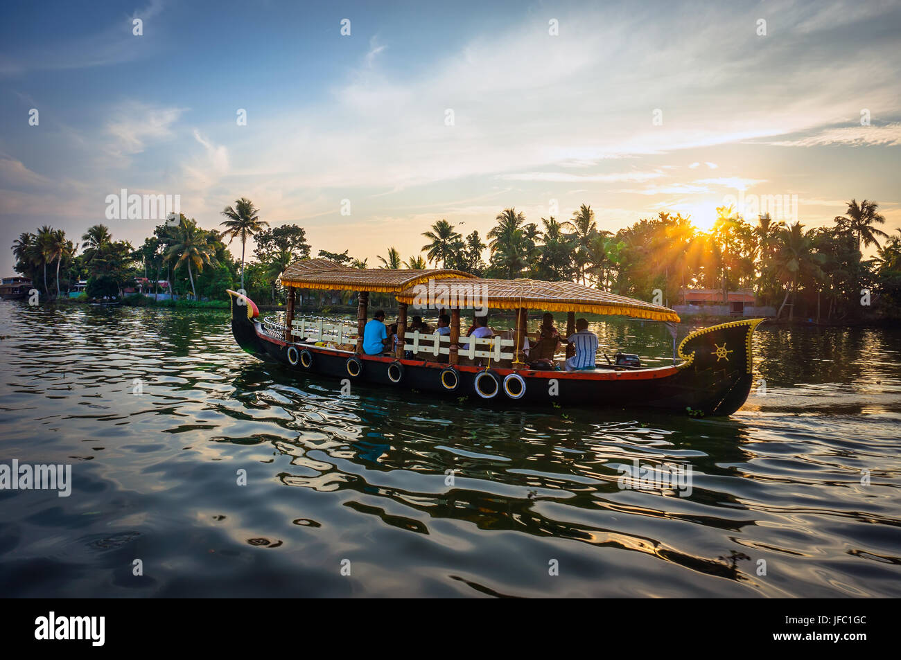 Boat carrying tourists floating down the river on a background of palm ...