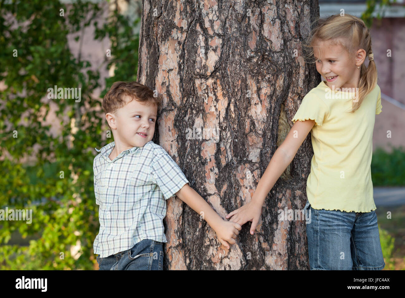 Two happy children playing near the tree at the day time. Concept ...