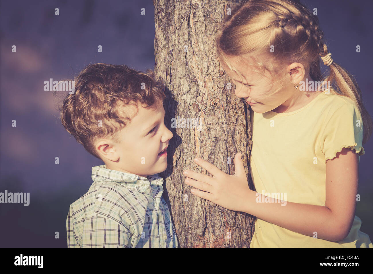 Two happy children playing near the tree at the day time. Concept Two ...