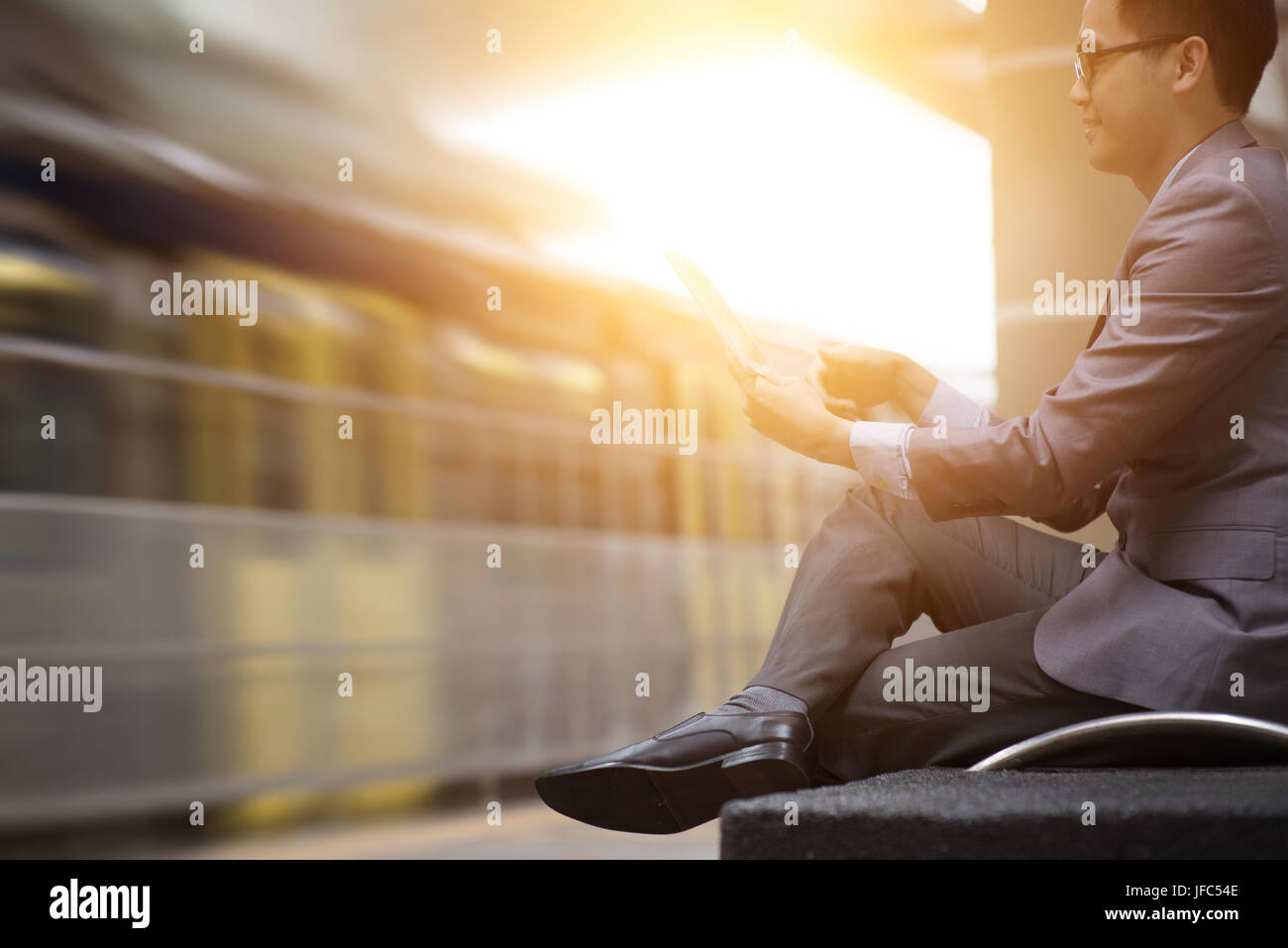 Asian businessman using digital tablet pc at railway station, with ...