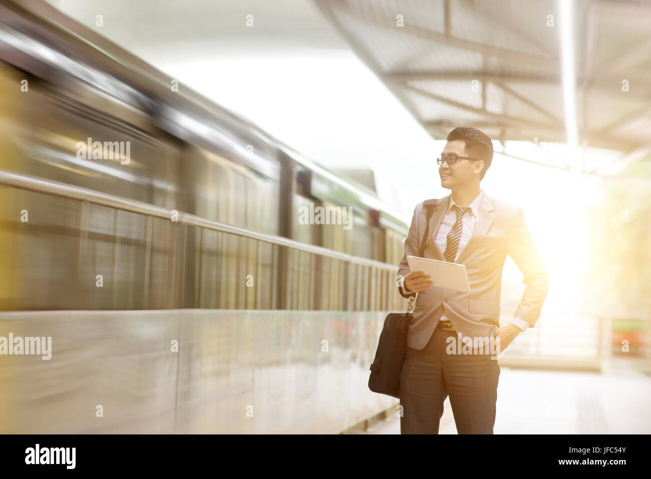 Asian businessman using digital tablet pc at commuter platform, with ...