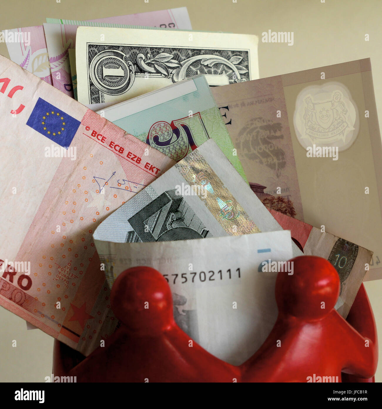 Red figures surrounding various currencies Stock Photo - Alamy