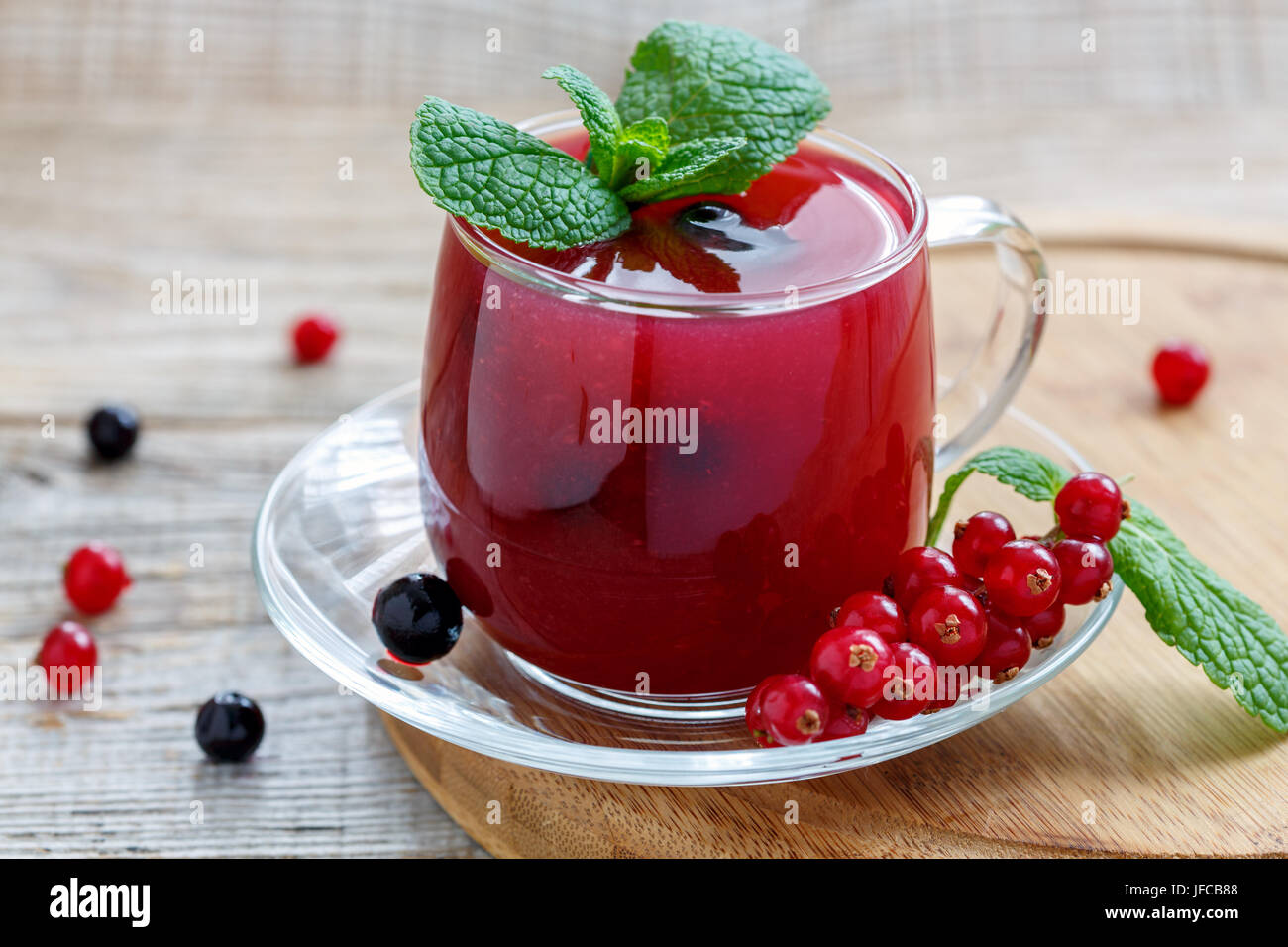 Glass cup with pudding of red and black currants and sprig of mint ...