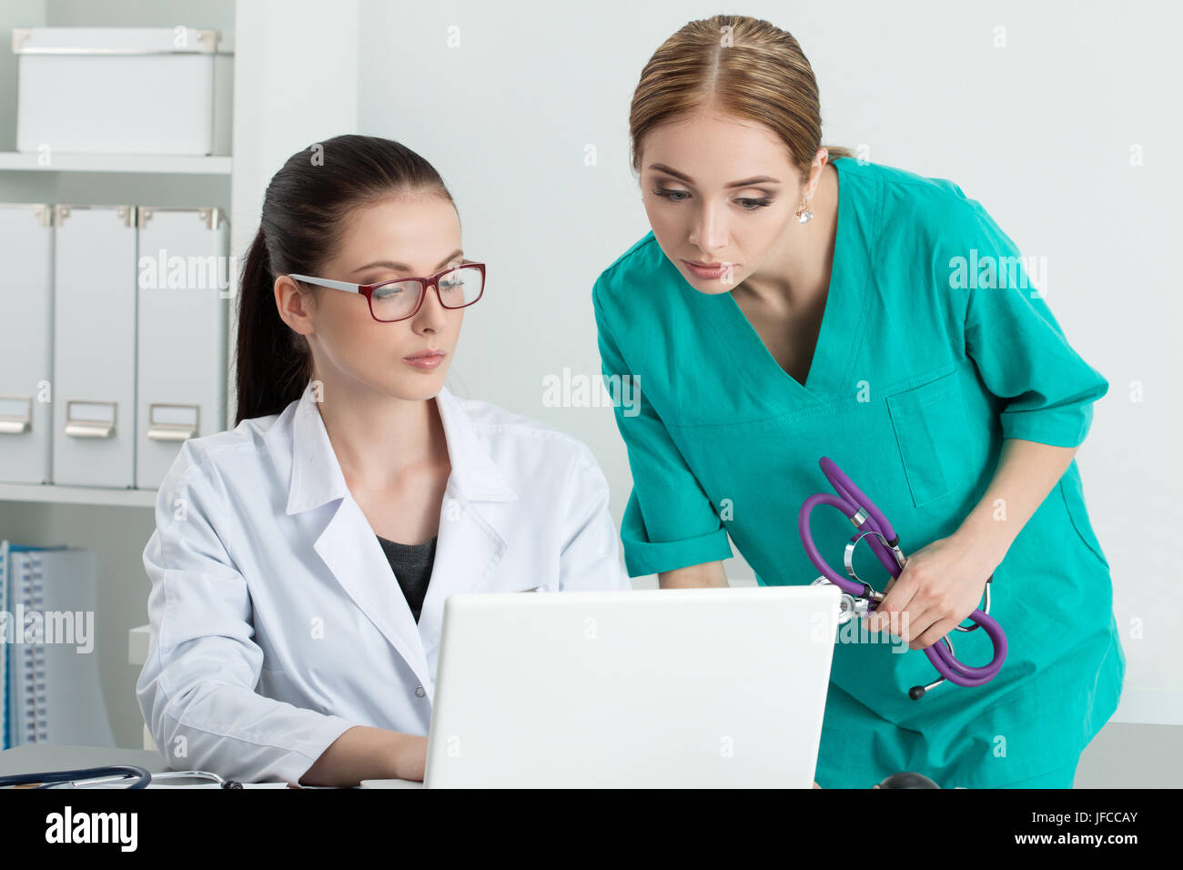 Female medicine doctor consulting with her pretty colleague looking at ...