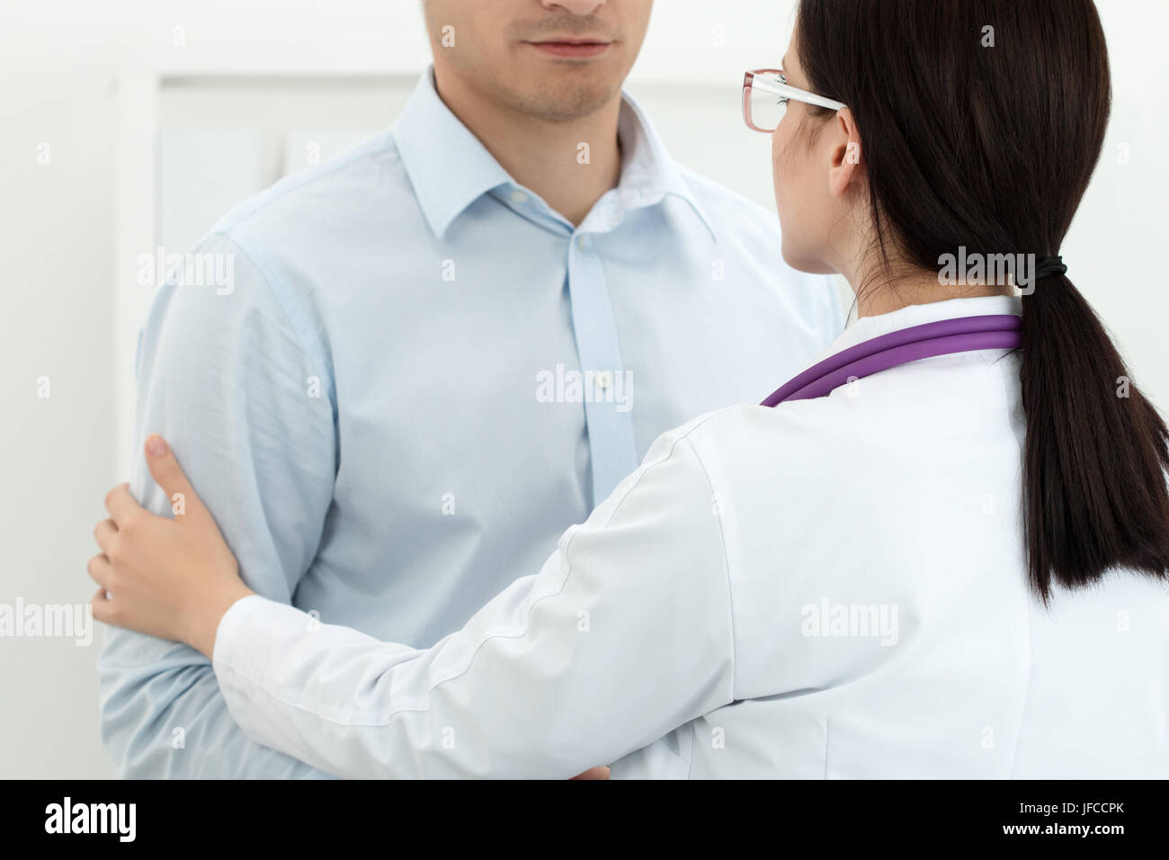 Friendly female doctor touching male patient's arm for encouragement ...