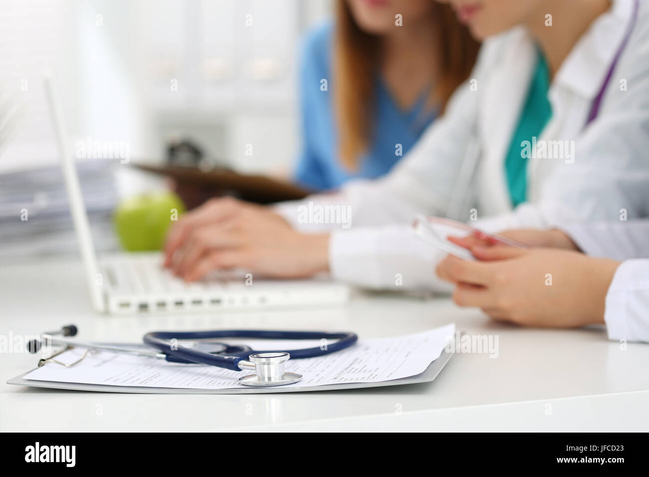 Medicine doctor's working table. Focus on stethoscope. Three female ...