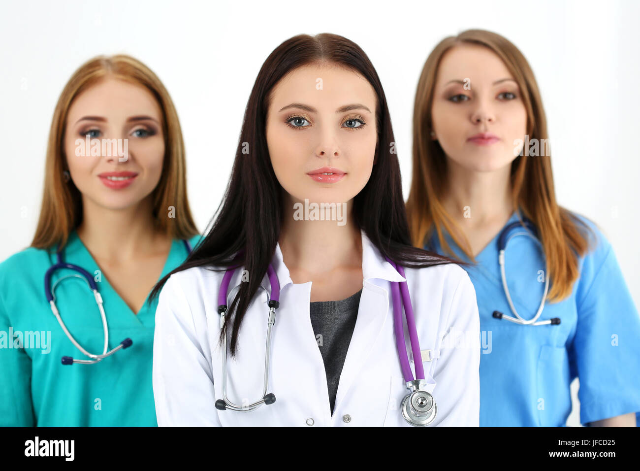 Portrait of young brunette female doctor surrounded by medical team ...