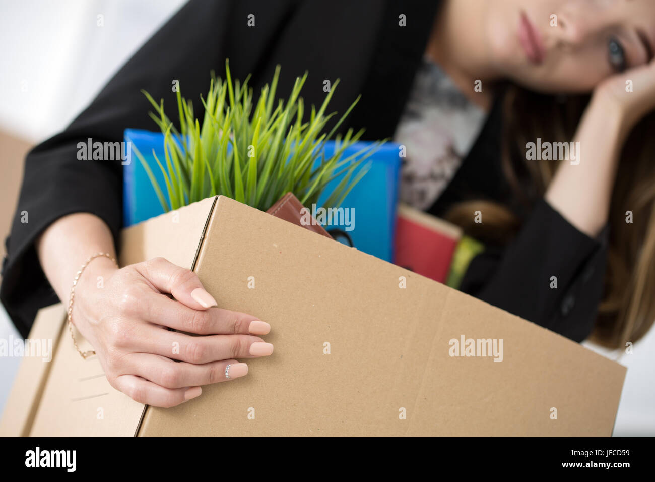 Young dismissed female worker in office holding carton box with her ...