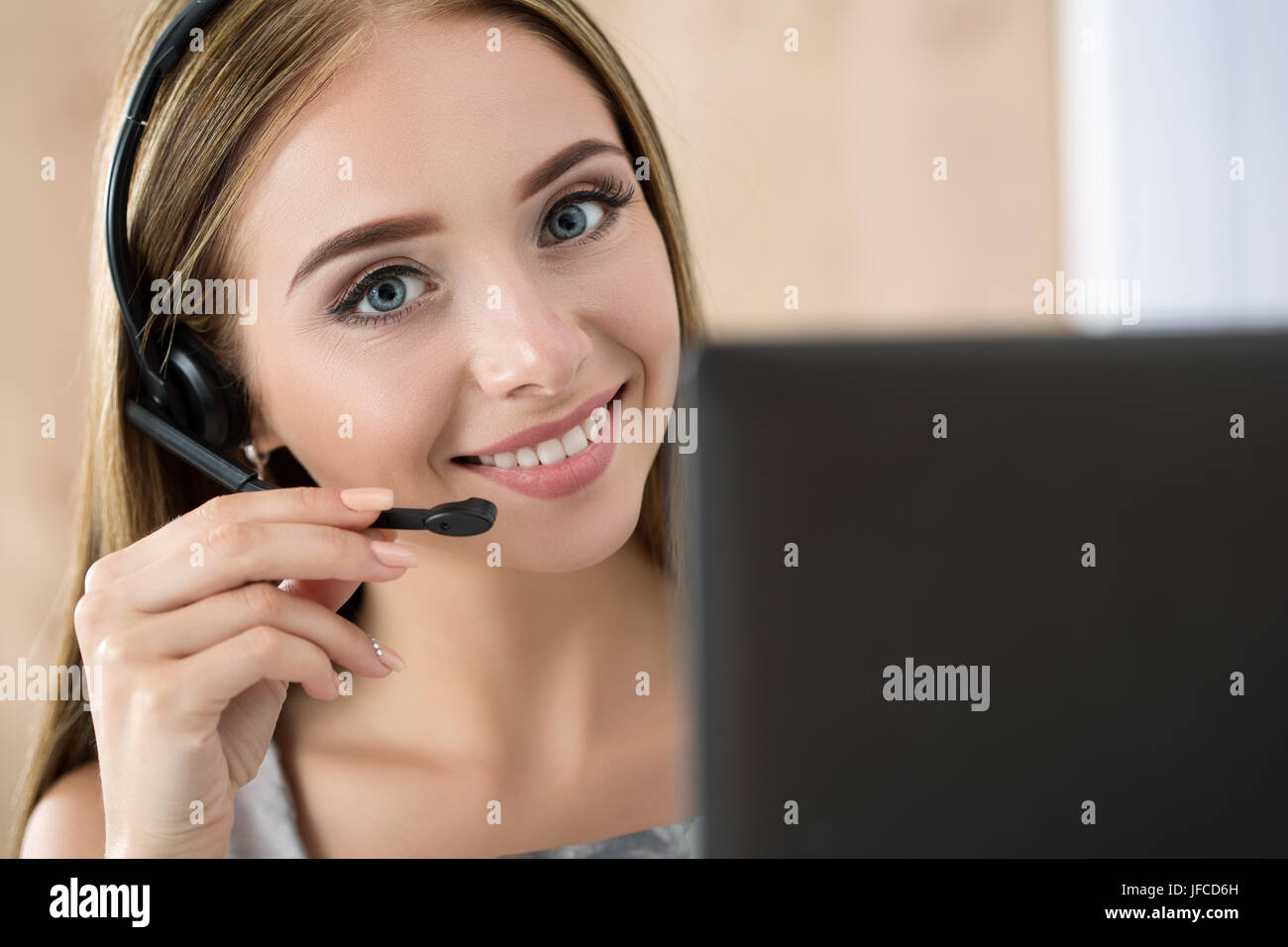 Portrait of beautiful call center operator at work. Woman with headset talking to someone online ...