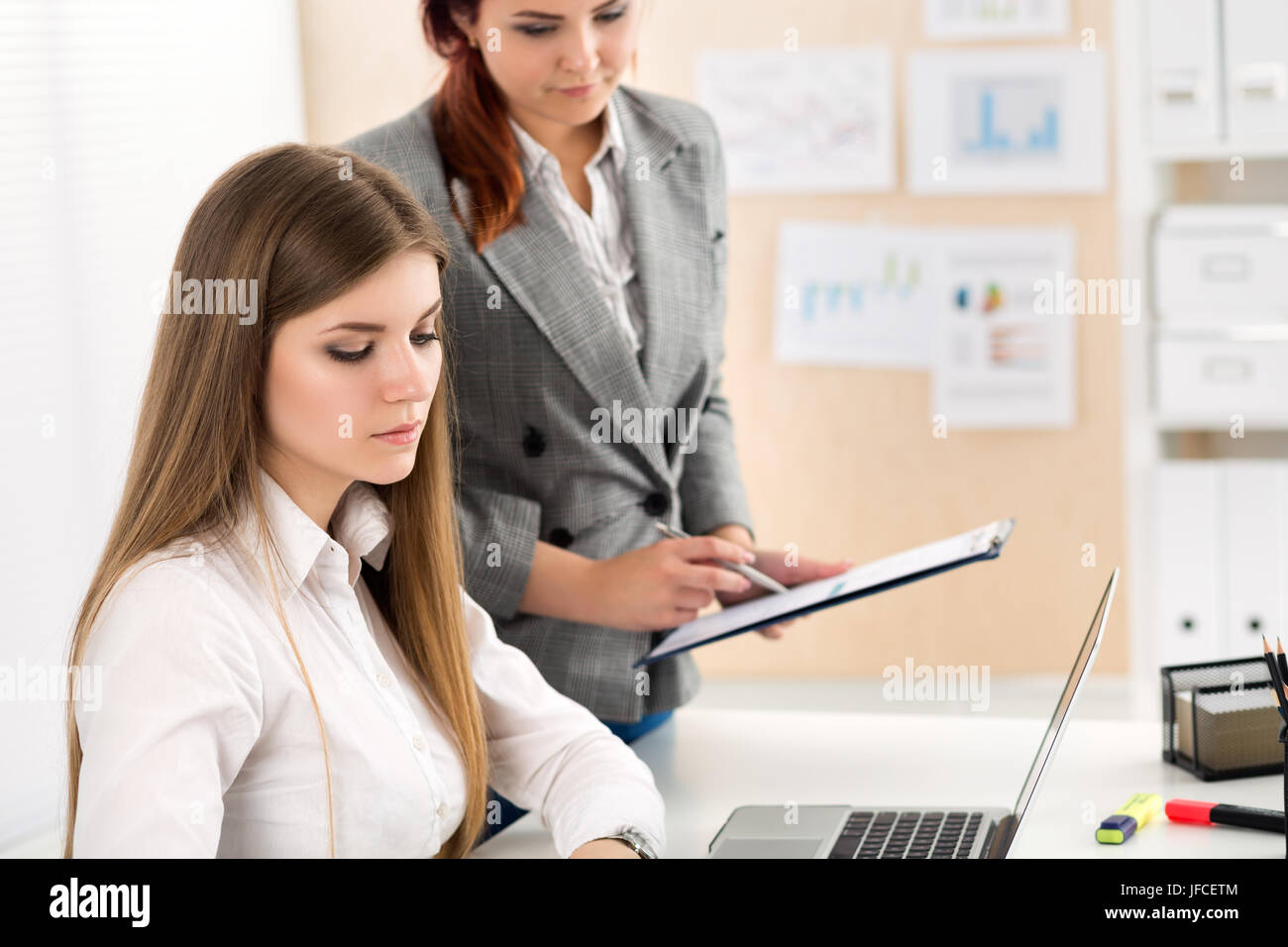 Two female auditors looking at financial report analyzing tables and ...