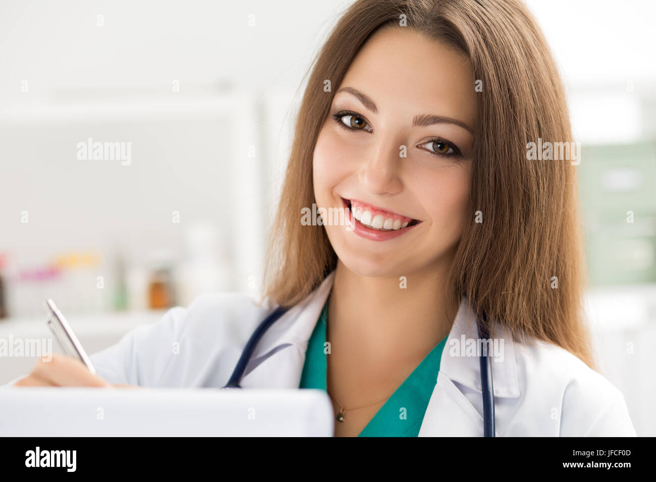 Portrait of smiling female medical doctor at work. Woman filling in ...