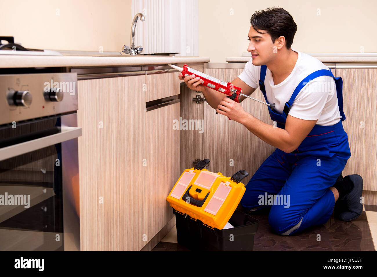 Young repairman working at the kitchen Stock Photo - Alamy