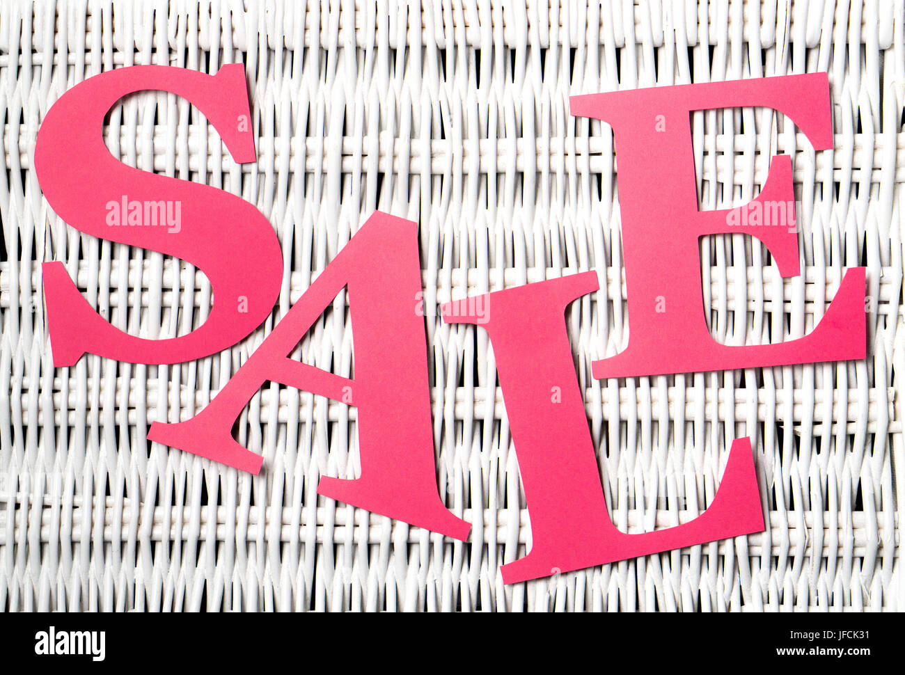 Pink red sale letters cut from cardboard paper on a white wicker ...